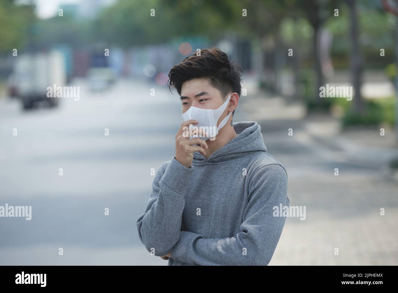 Portrait of young Asian man in face mask standing outdoors Stock Photo ...
