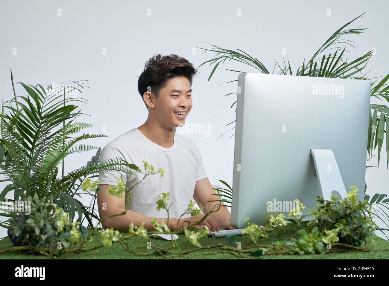 Happy excited Vietnamese young man working on computer with various ...