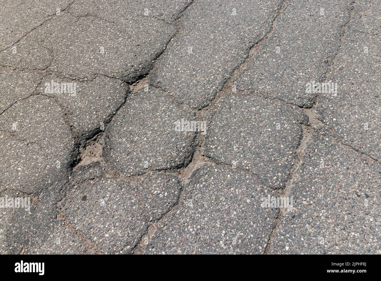 An old paved road with a lot of holes and damage, very poor quality of ...