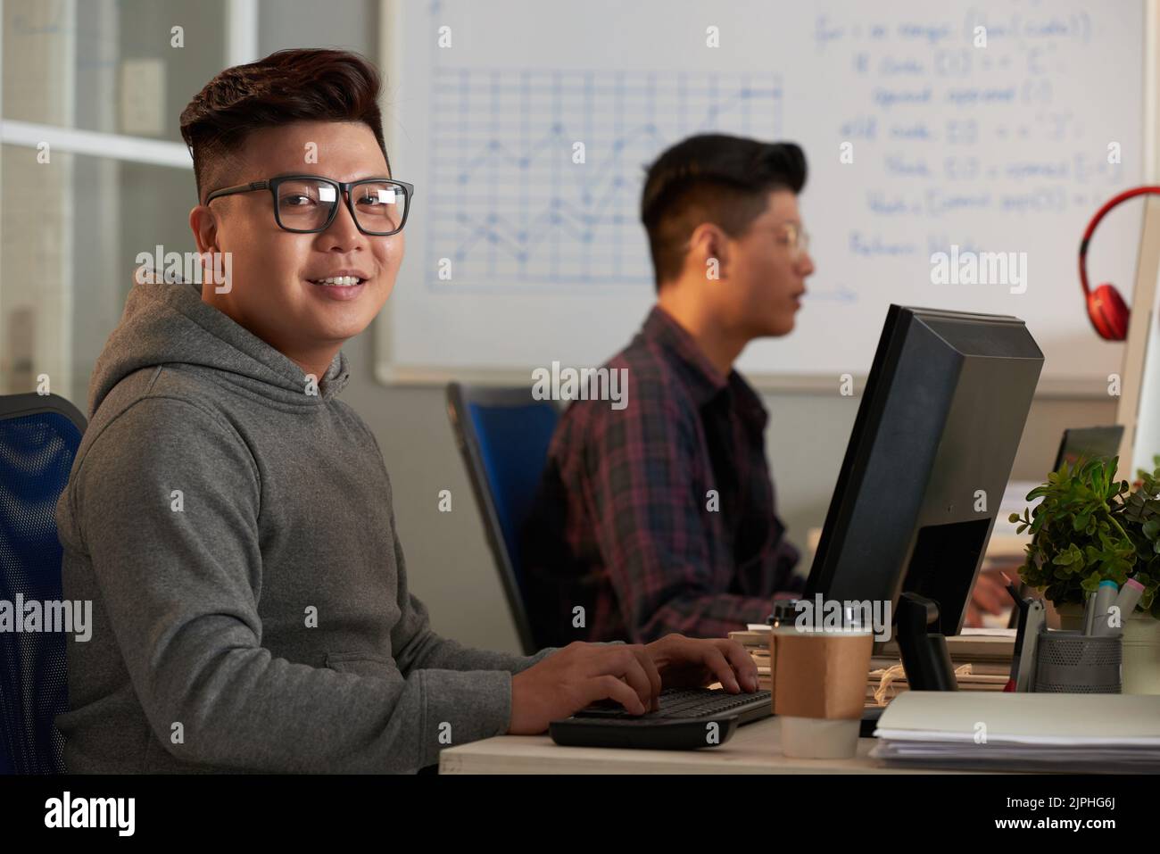Smiling Asian student wearing eyeglasses looking at camera while ...