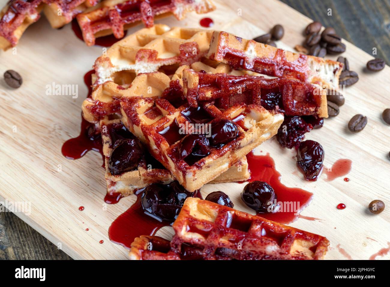 soft waffles with red cherry jam on a serving board, cooking with soft ...
