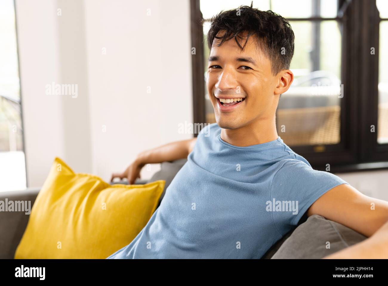 Portrait of happy biracial man sitting on sofa, looking at camera and smiling Stock Photo - Alamy