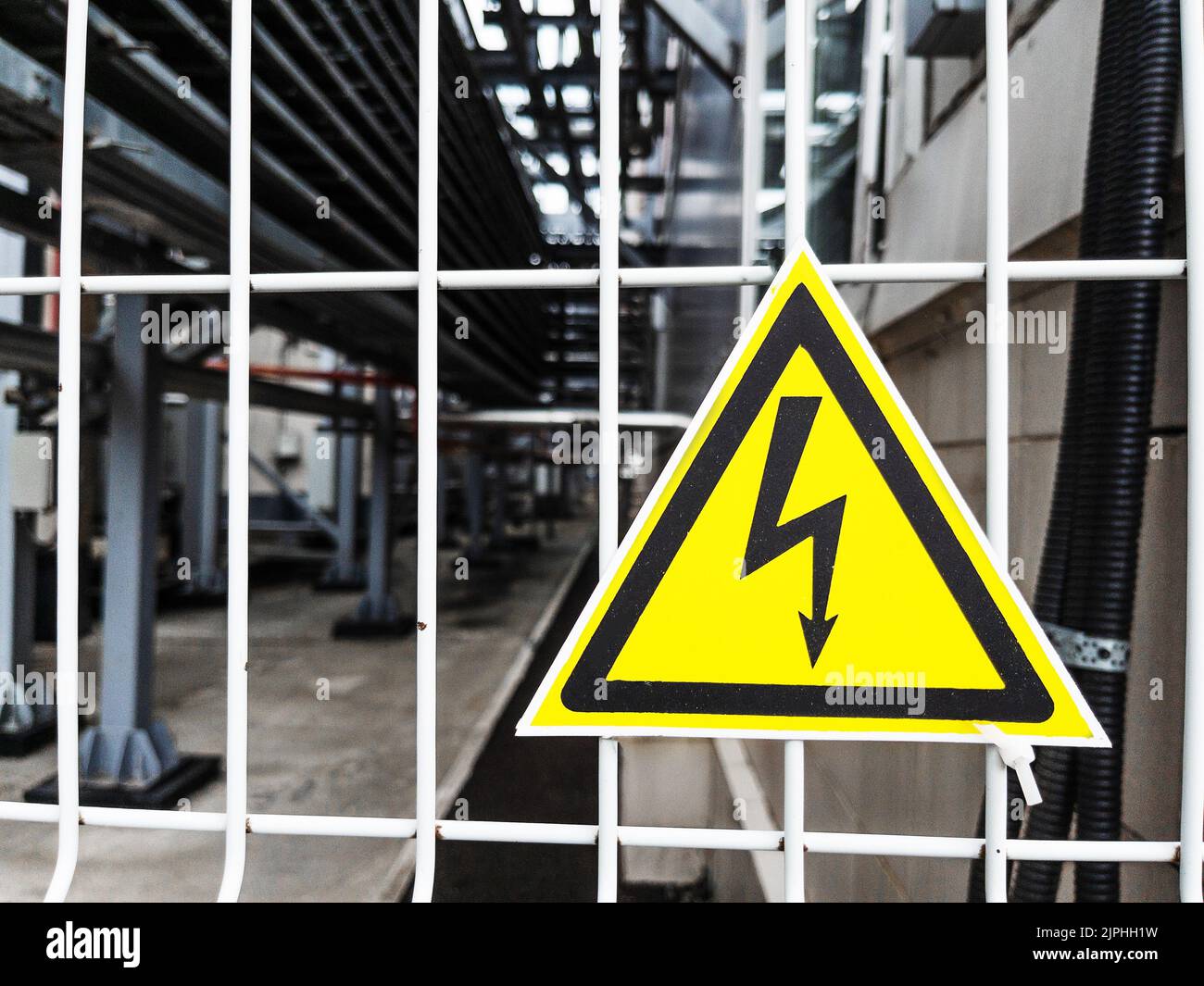 Danger Sign High voltage in the yellow triangle on the metal fence of ...