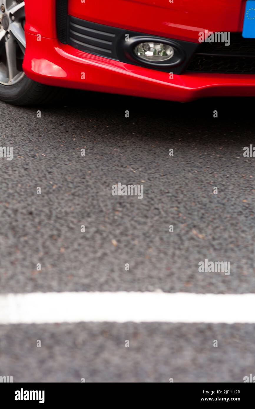 Red sports car ready to move in front of white line Stock Photo - Alamy