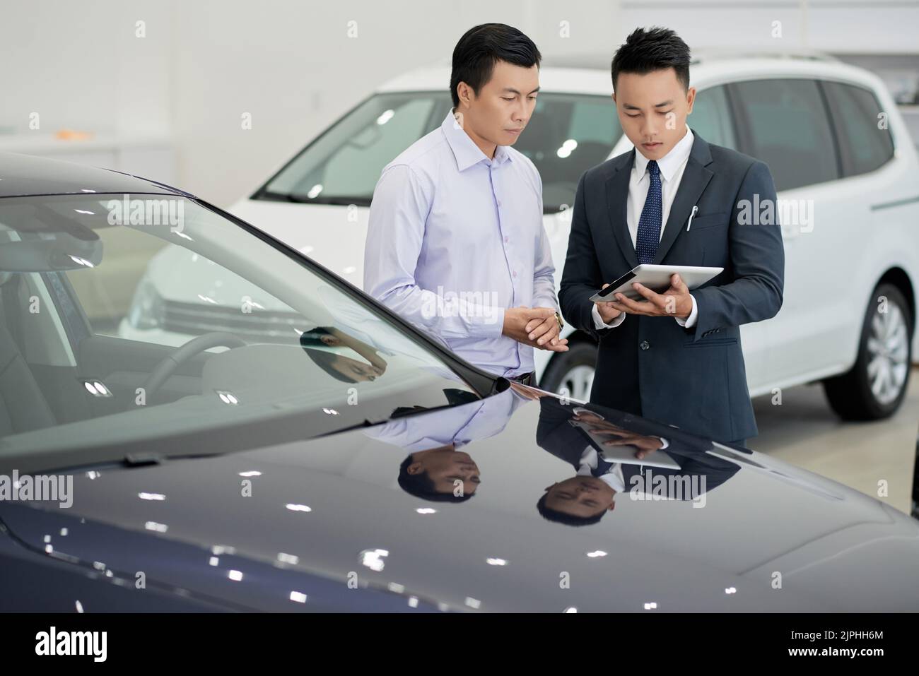 Young salesman telling customer features of of new car Stock Photo - Alamy