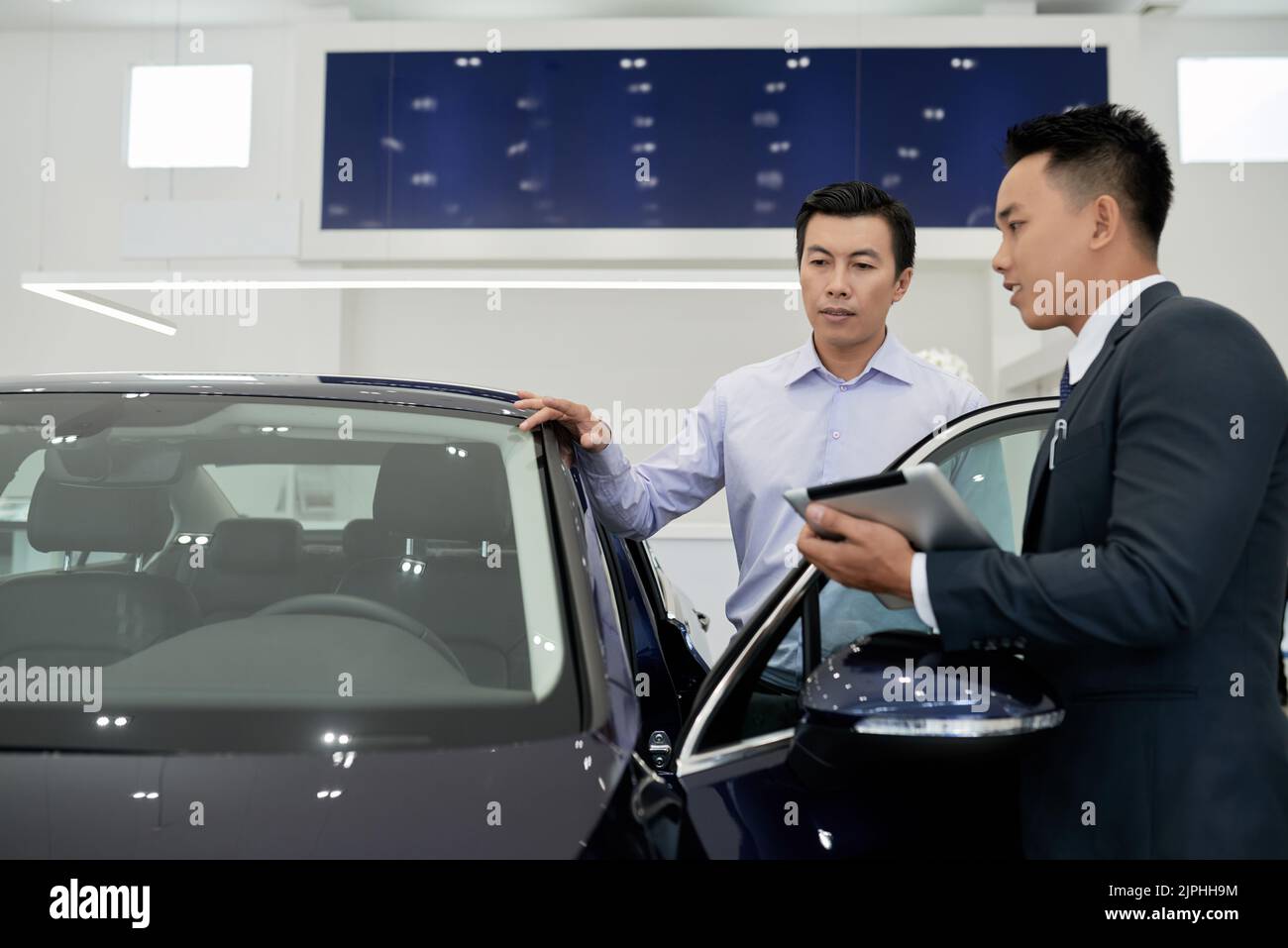 Dealer and customer discussing car at auto show Stock Photo - Alamy