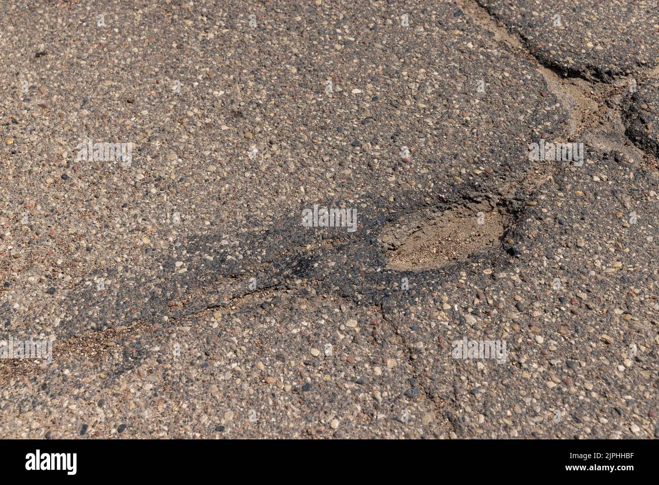 An old paved road with a lot of holes and damage, very poor quality of ...