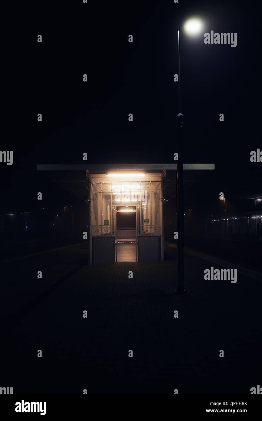 A vertical shot of an illuminated booth in a train station at night ...
