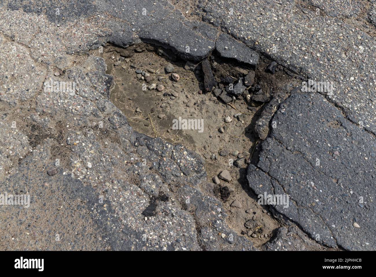 An old paved road with a lot of holes and damage, very poor quality of ...