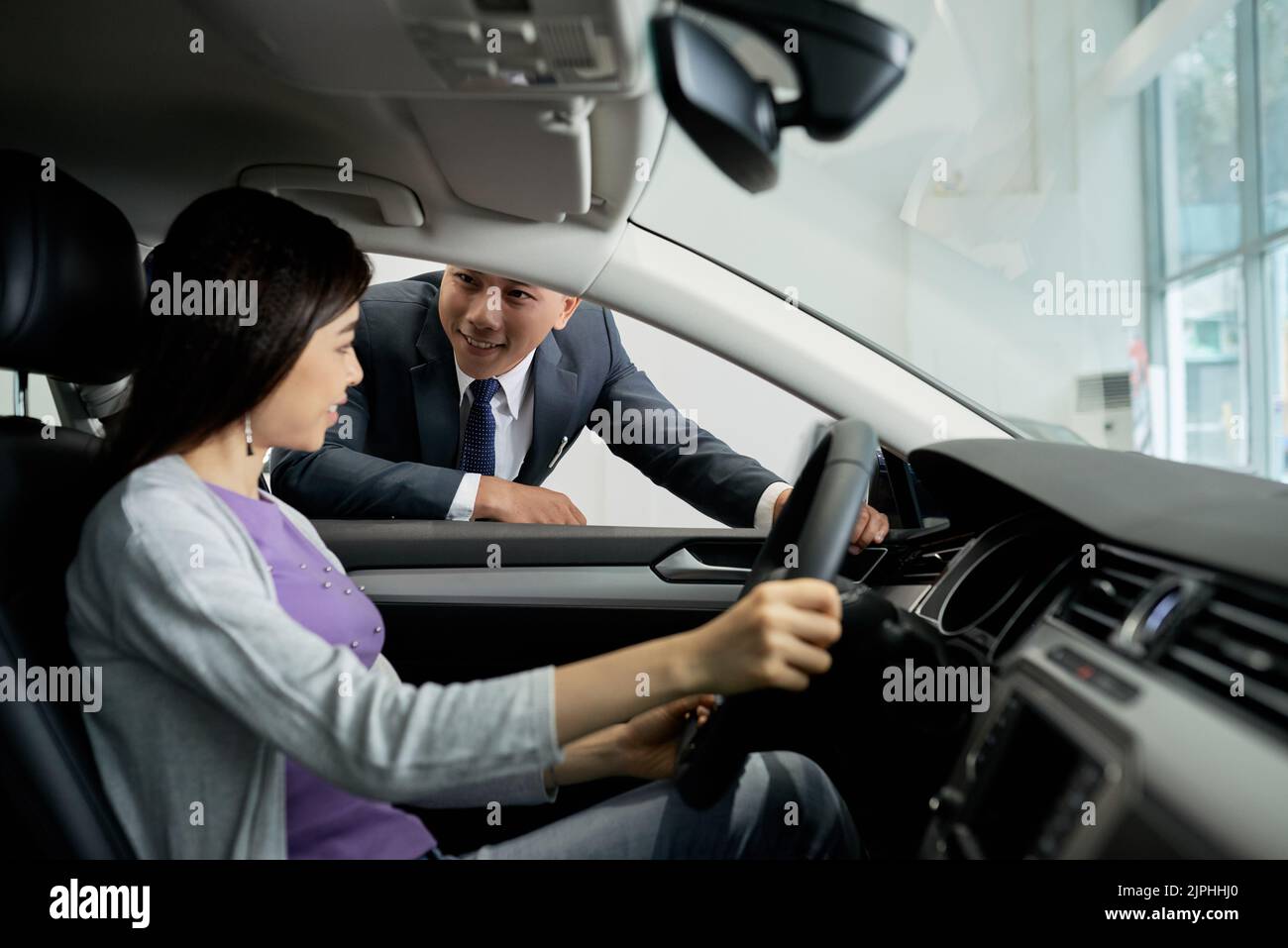 Salesman talking to female customer sitting in car Stock Photo - Alamy