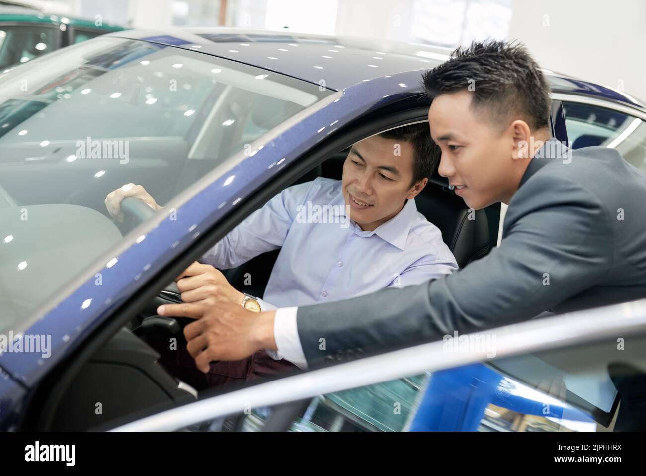 Vitenamese salesman explaining buttons on dashboard to the customer ...