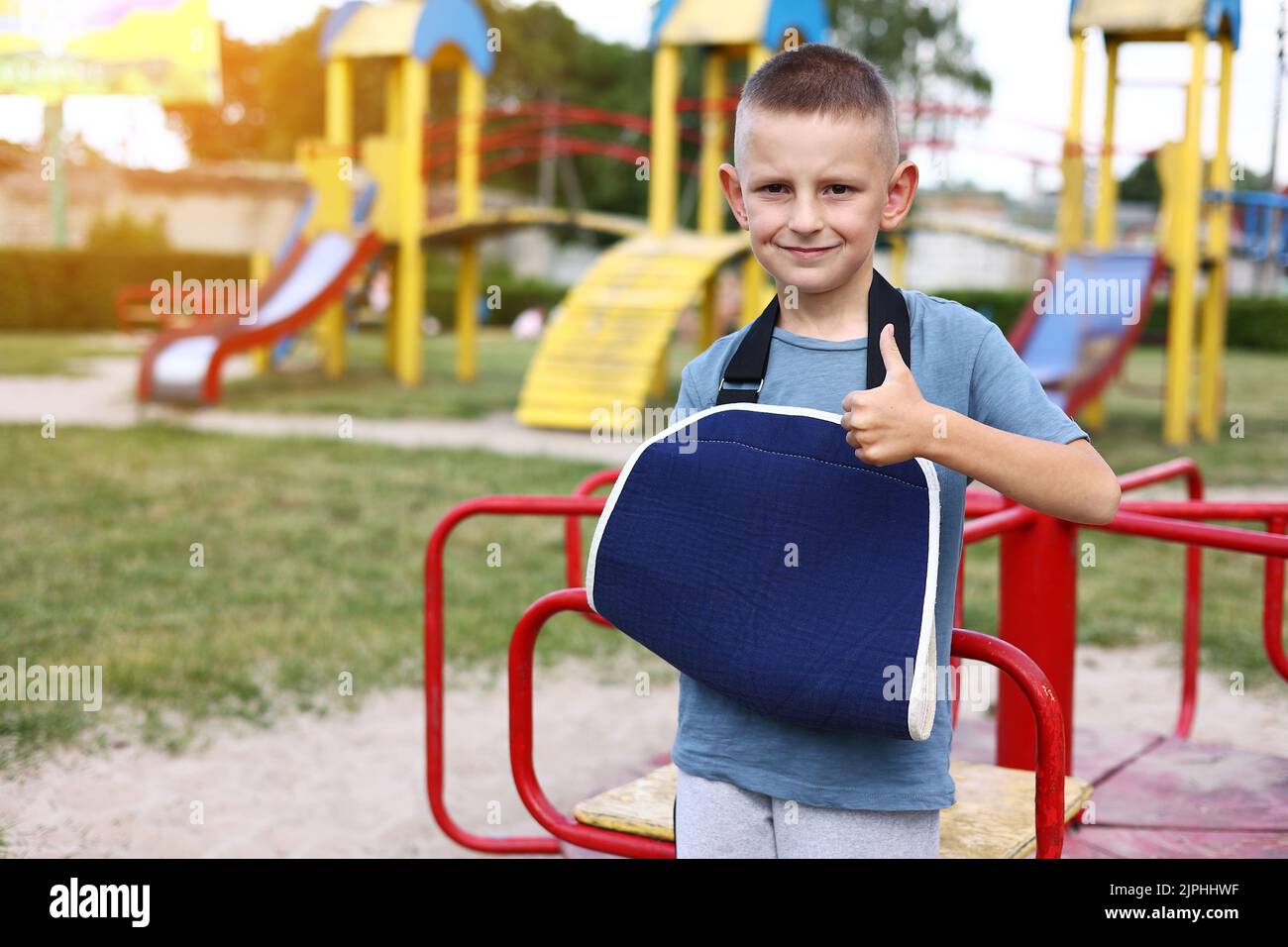 happy child with broken limb arm outdoors on playground background ...