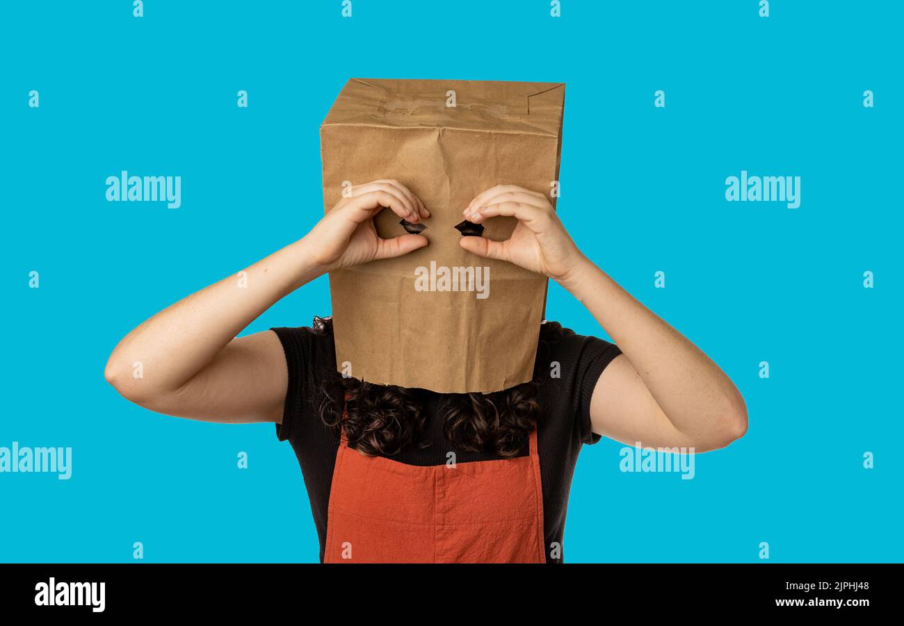 Woman wearing paper bag over her head holding her hands near eyes like ...