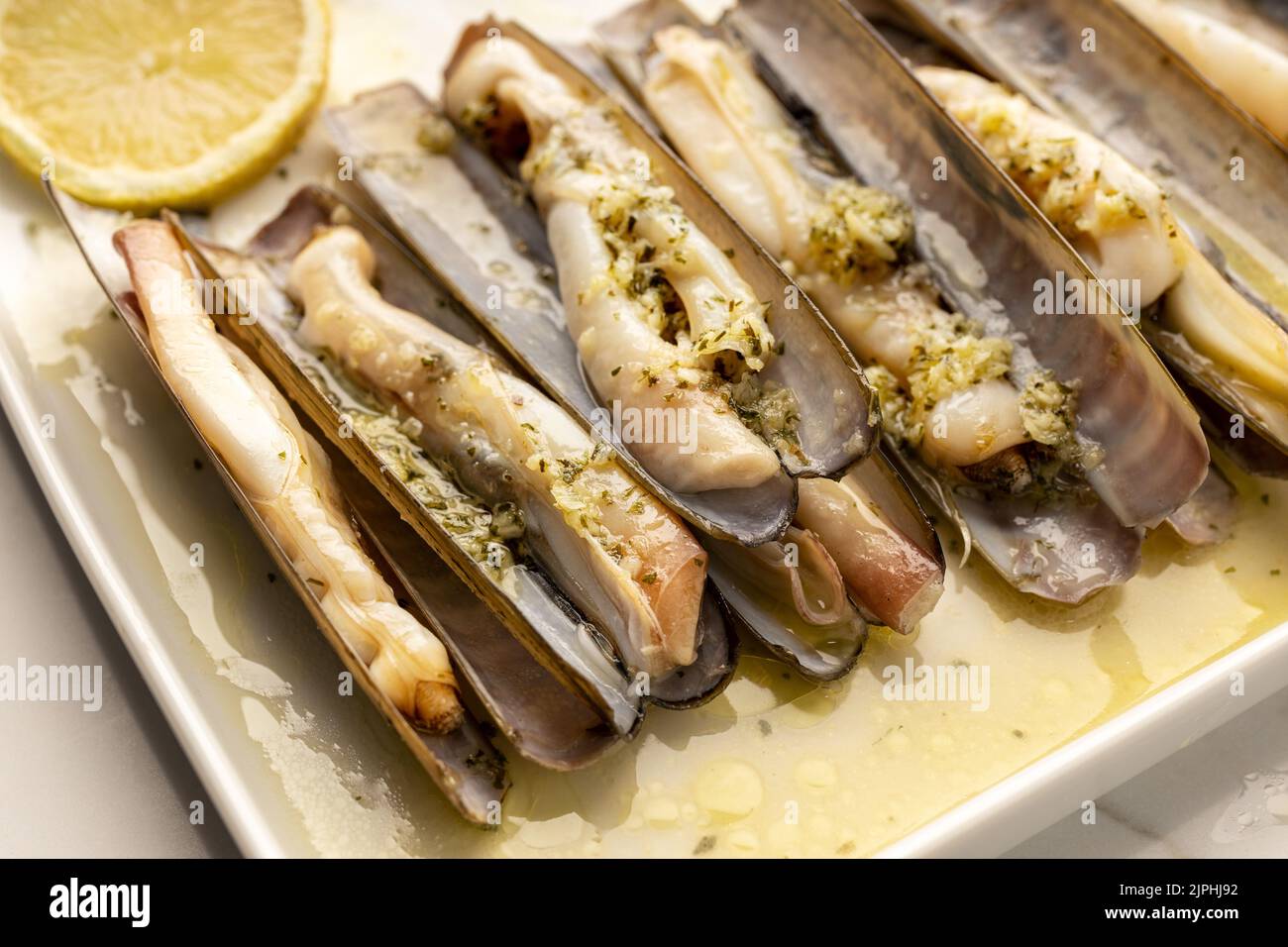 Coked Ensis Clams with garlic and herbs on plate. Typical dish of ...