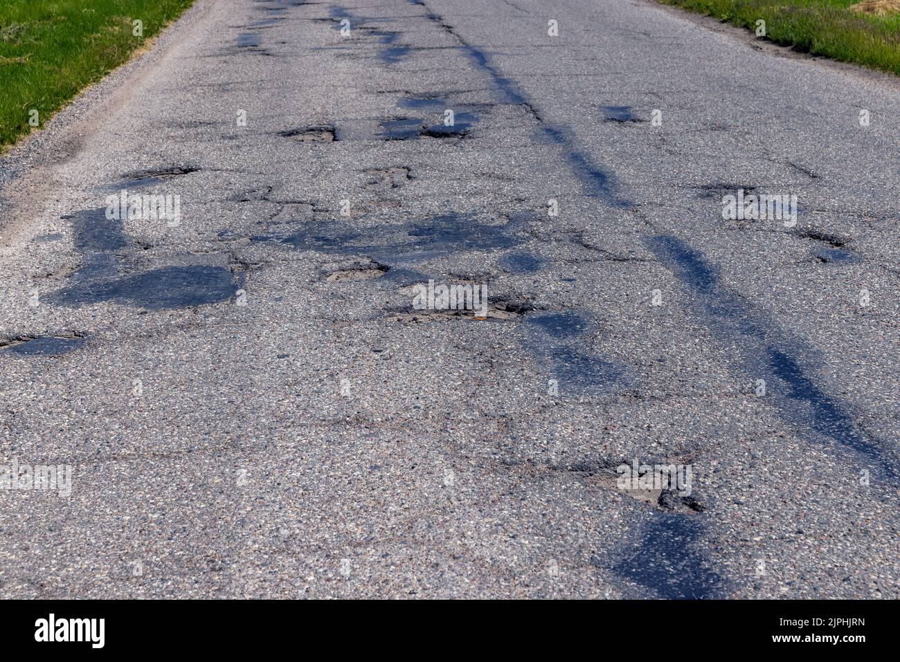 An old paved road with a lot of holes and damage, very poor quality of ...