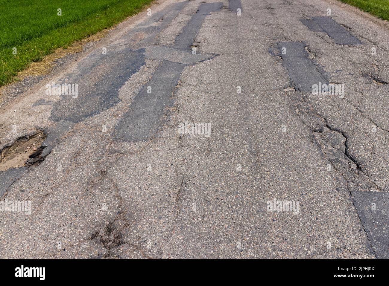 An old paved road with a lot of holes and damage, very poor quality of ...