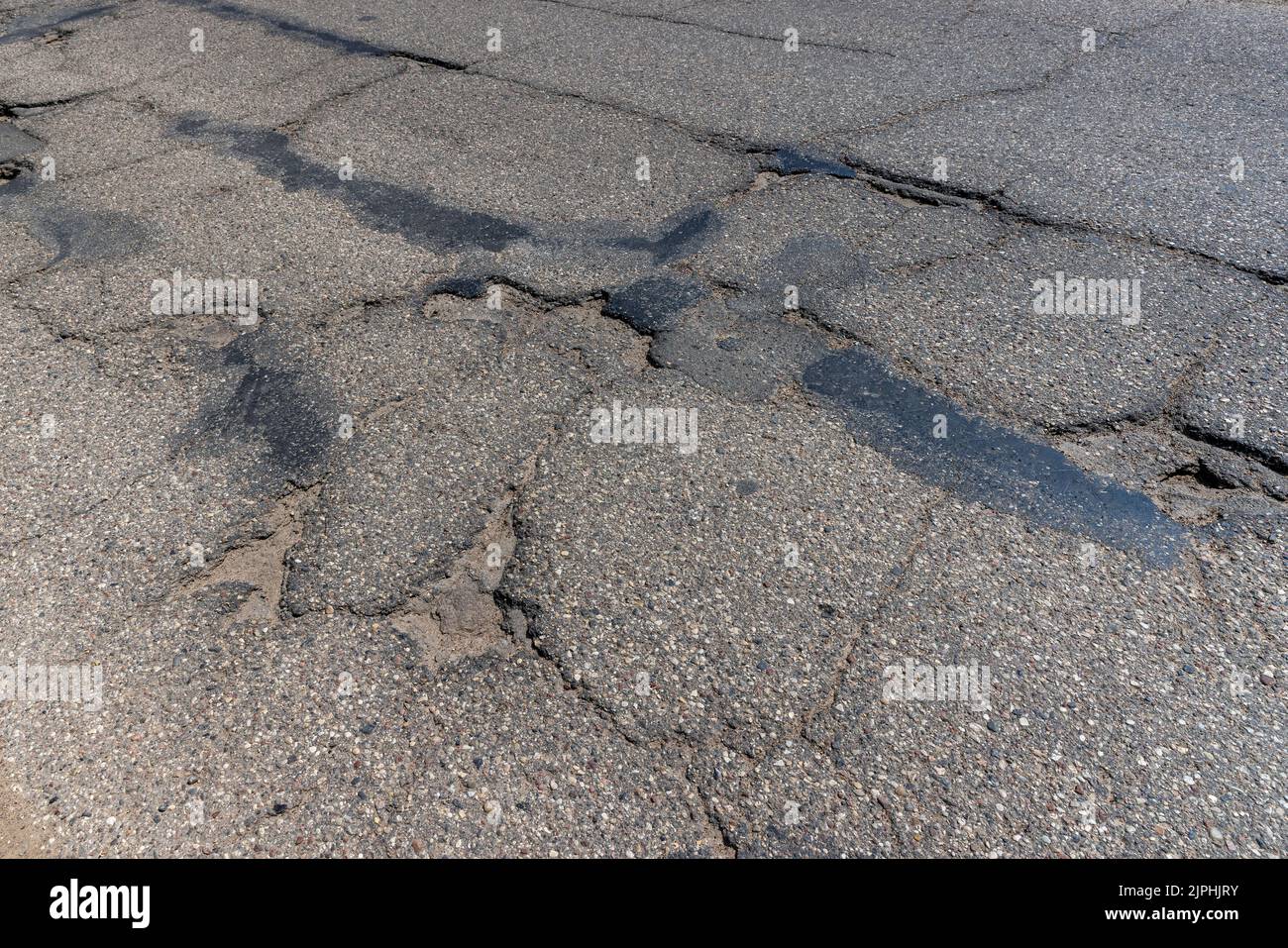An old paved road with a lot of holes and damage, very poor quality of ...