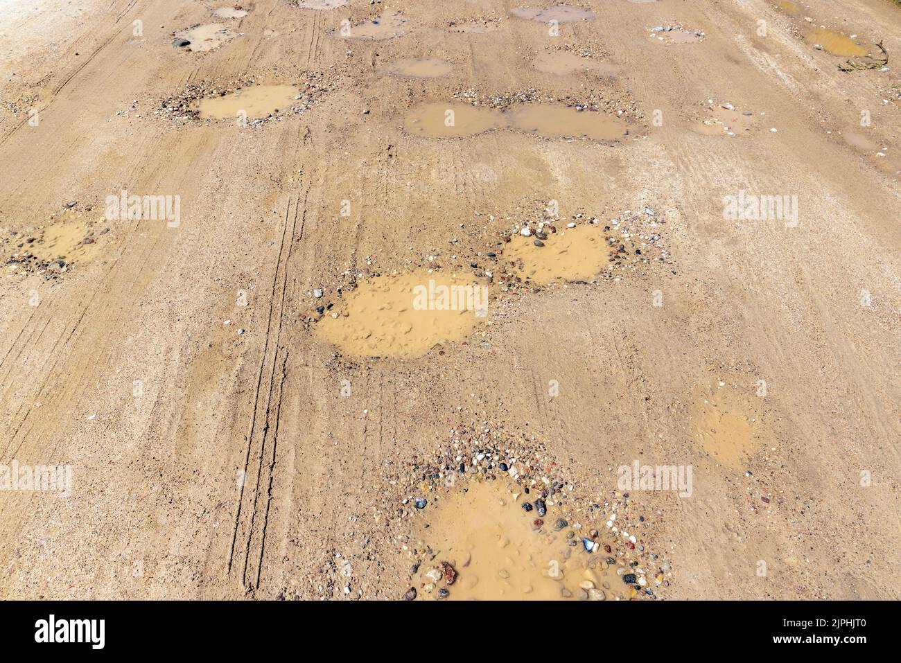 a dirt road with a lot of water holes, puddles on a dirt road after ...