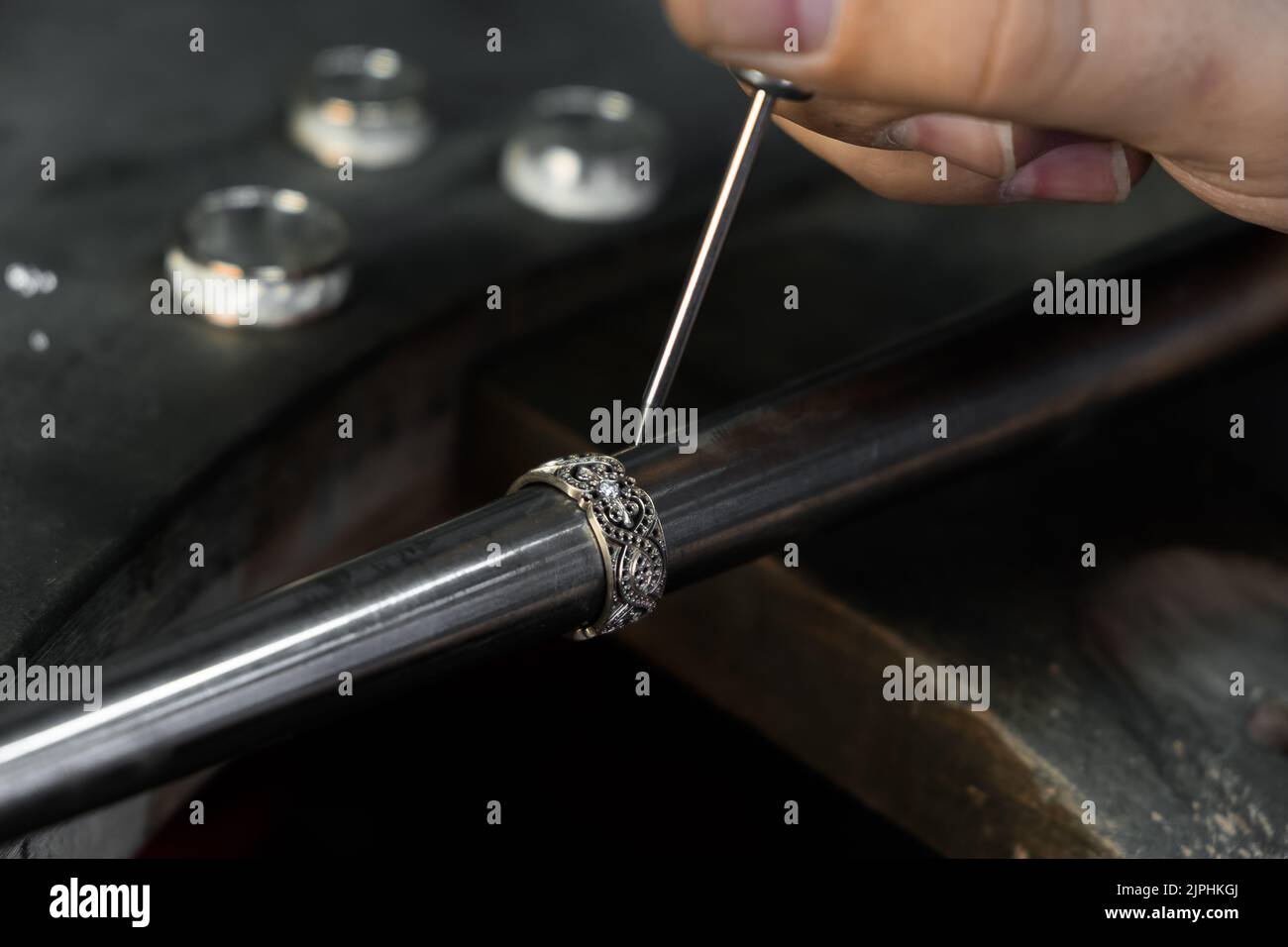 Close-up of hand of a goldsmith setting the diamond on the ring. Craft ...