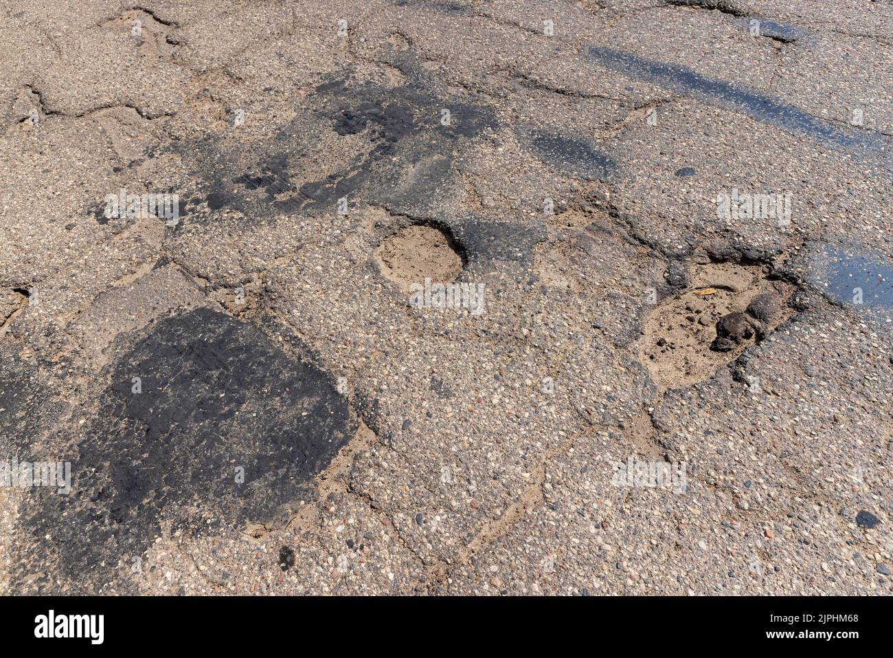 An old paved road with a lot of holes and damage, very poor quality of ...