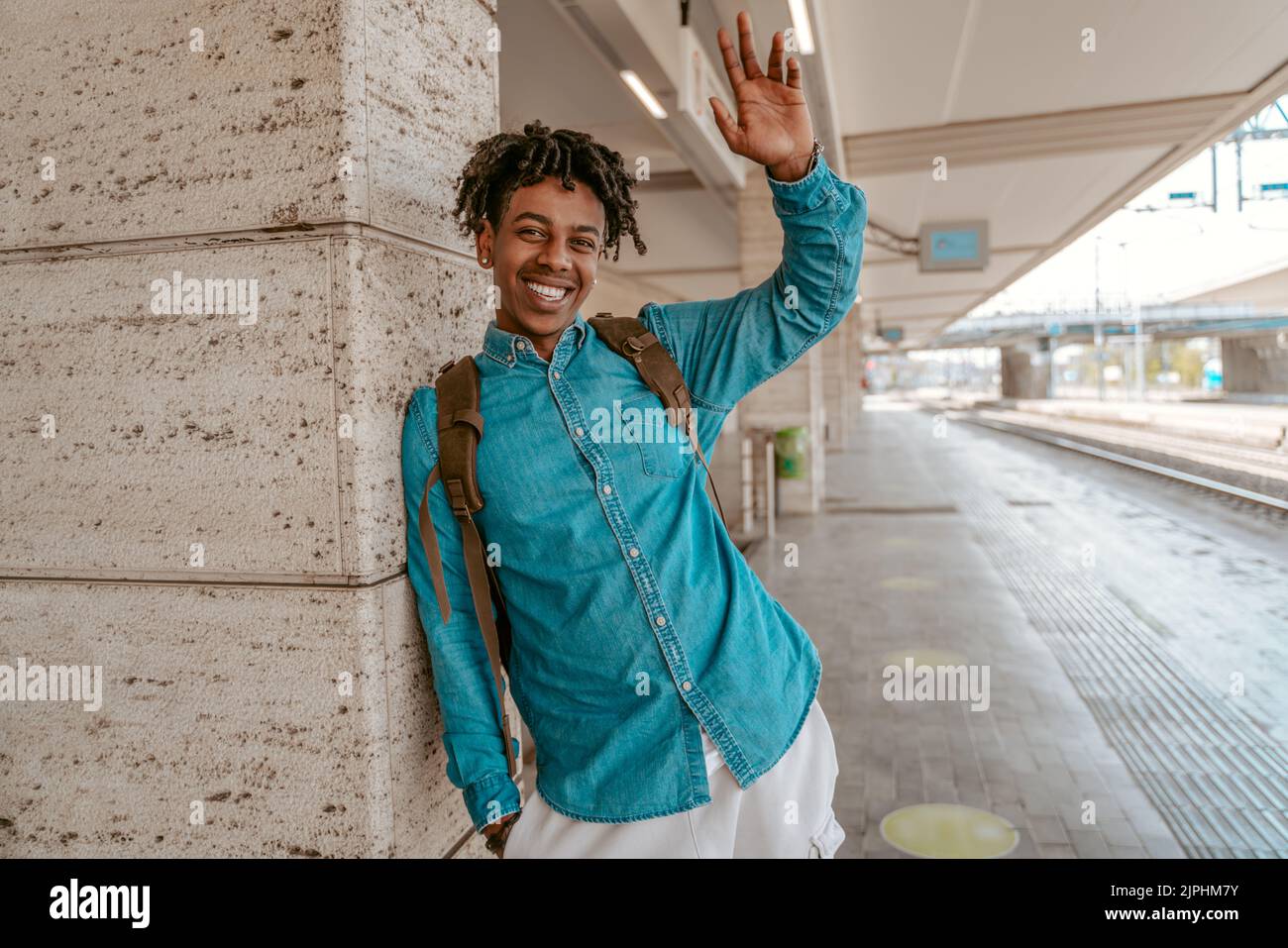Guy waving hand standing on railway platform Stock Photo - Alamy