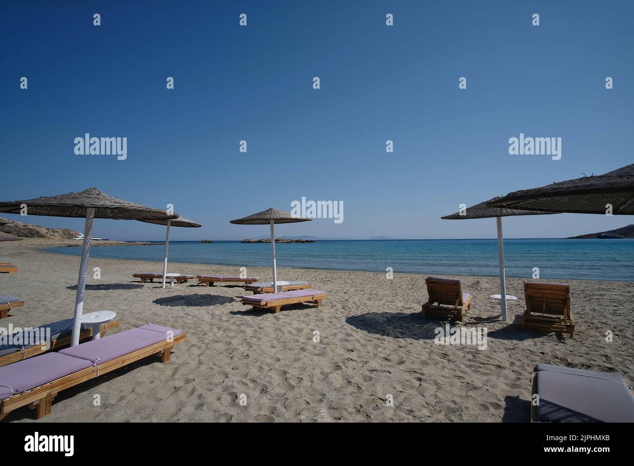 Empty sun beds and a sun umbrellas at the amazing beach of Manganari in ...