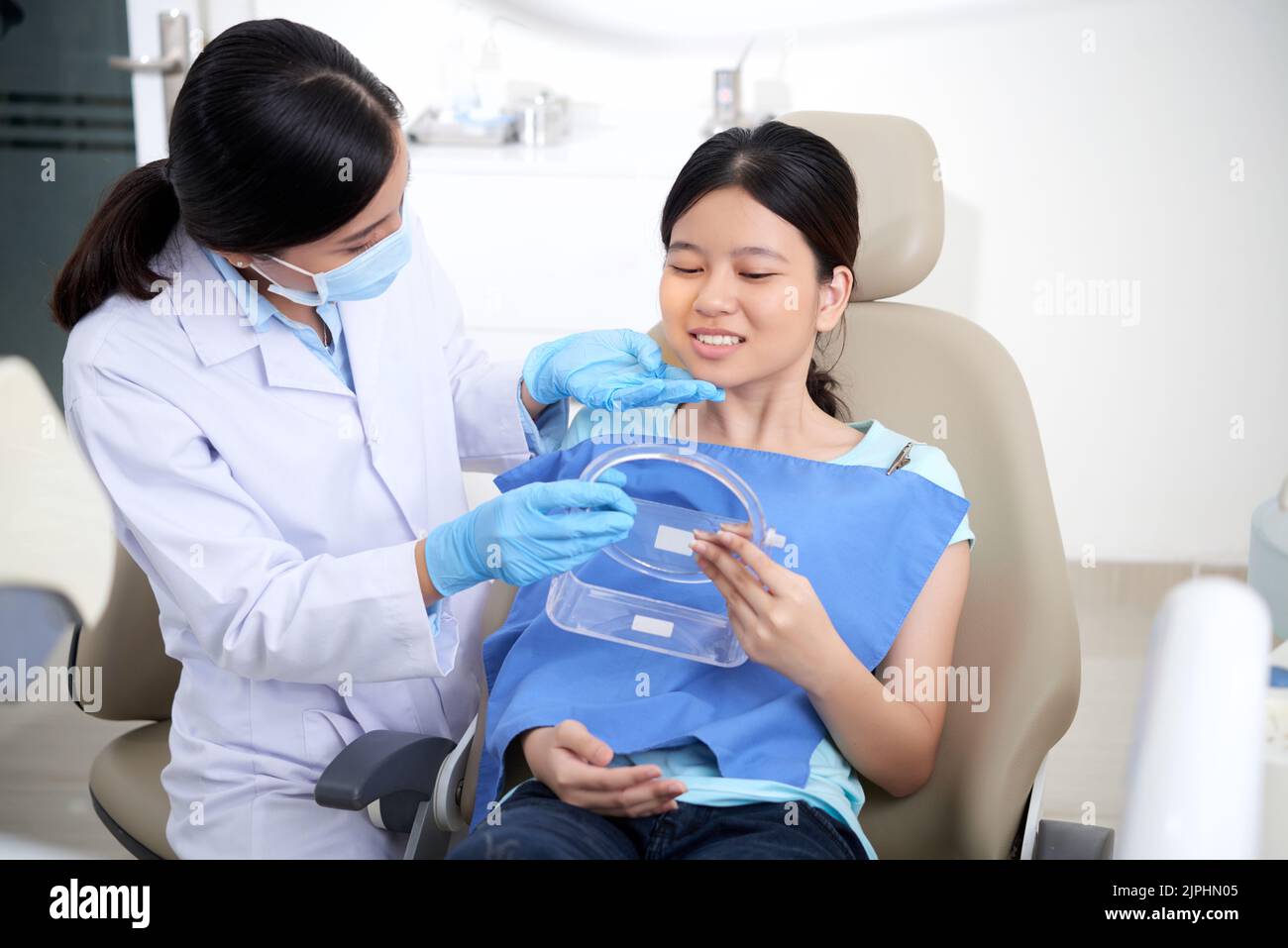 Dentist giving mirror to teenage patient after treatment Stock Photo ...