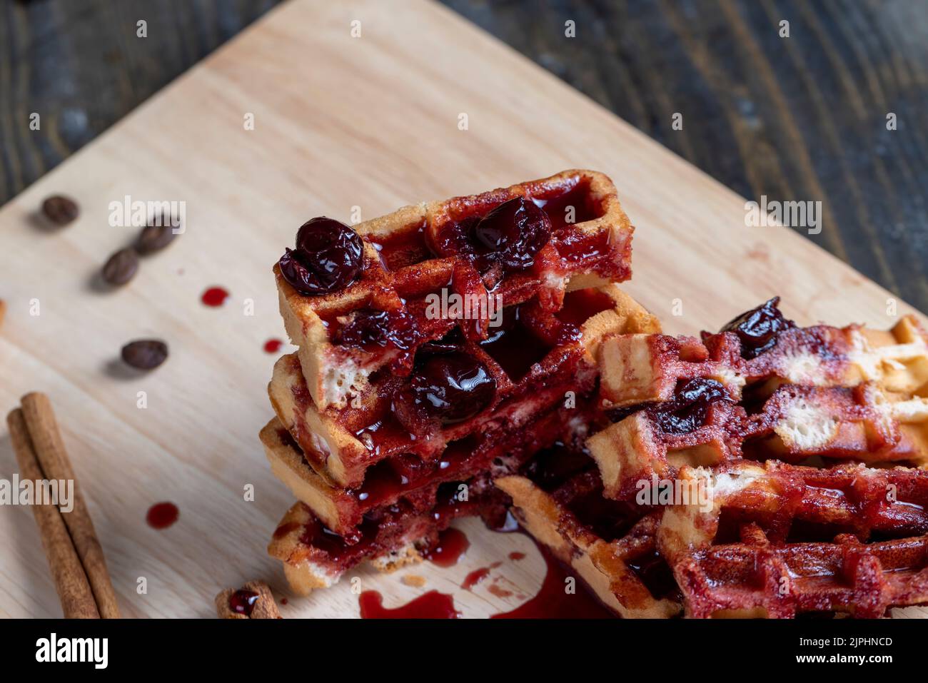 soft waffles with red cherry jam on a serving board, cooking with soft ...