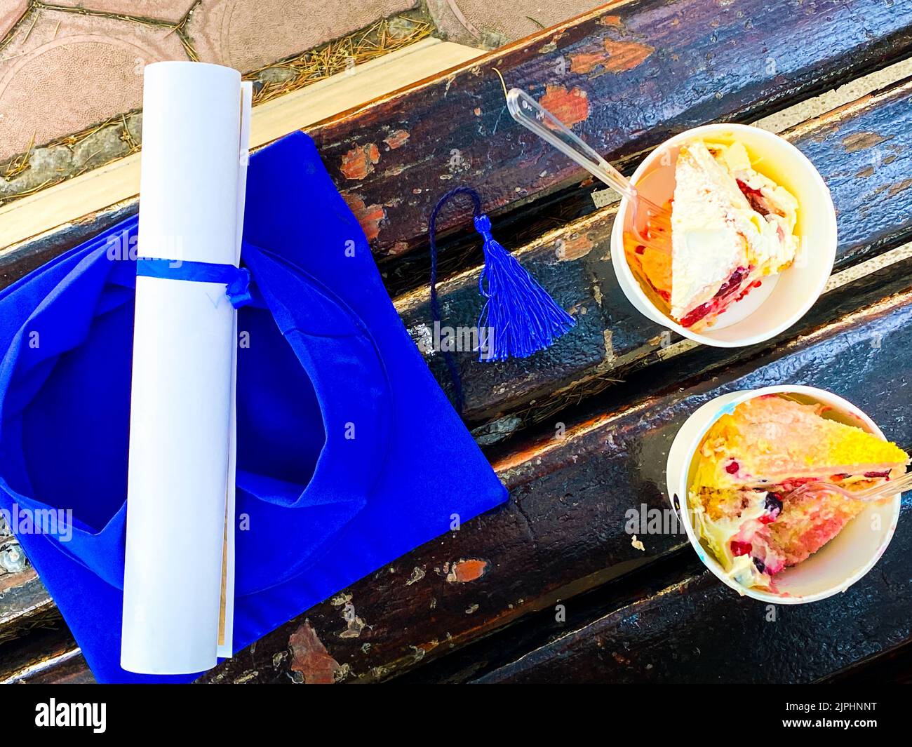 Graduation oath paper with tassel and two party cakes in paper cups on ...