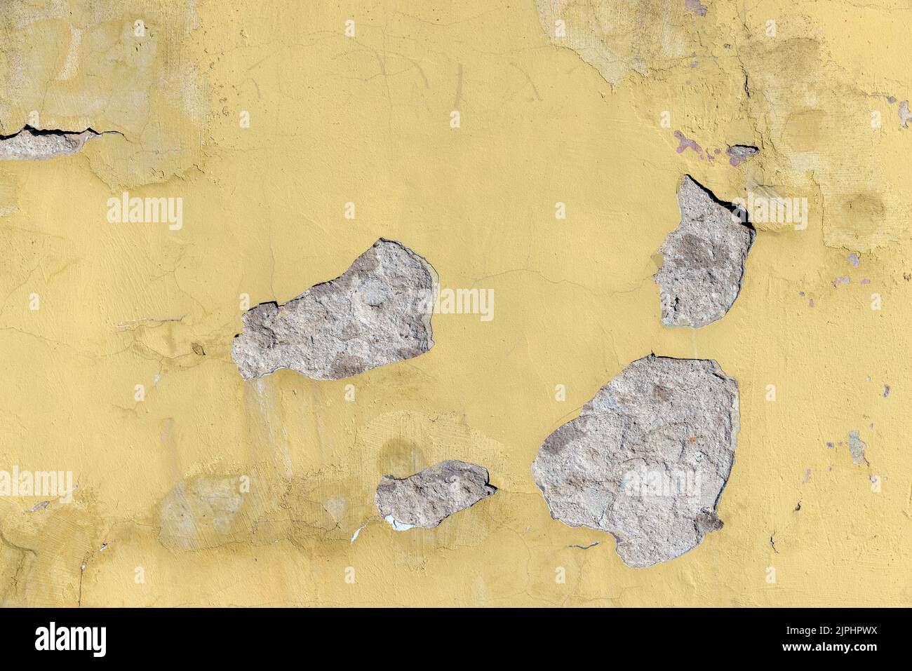 Damaged yellow plaster of a concrete wall, part of a damaged building ...