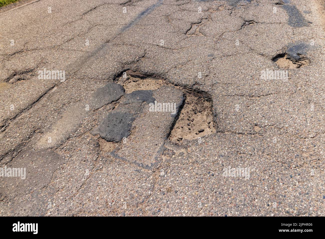 An old paved road with a lot of holes and damage, very poor quality of ...