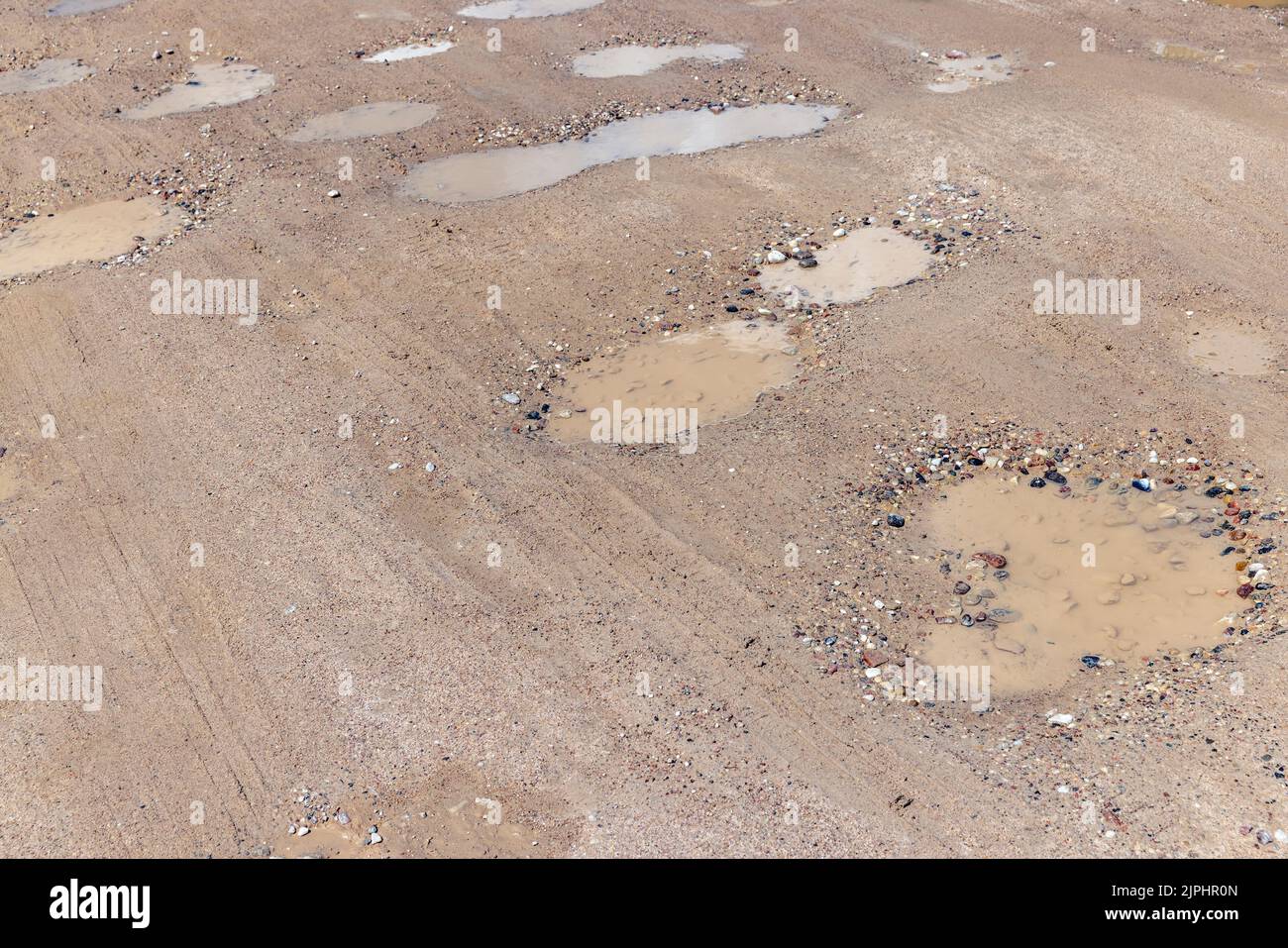 a dirt road with a lot of water holes, puddles on a dirt road after rains Stock Photo - Alamy