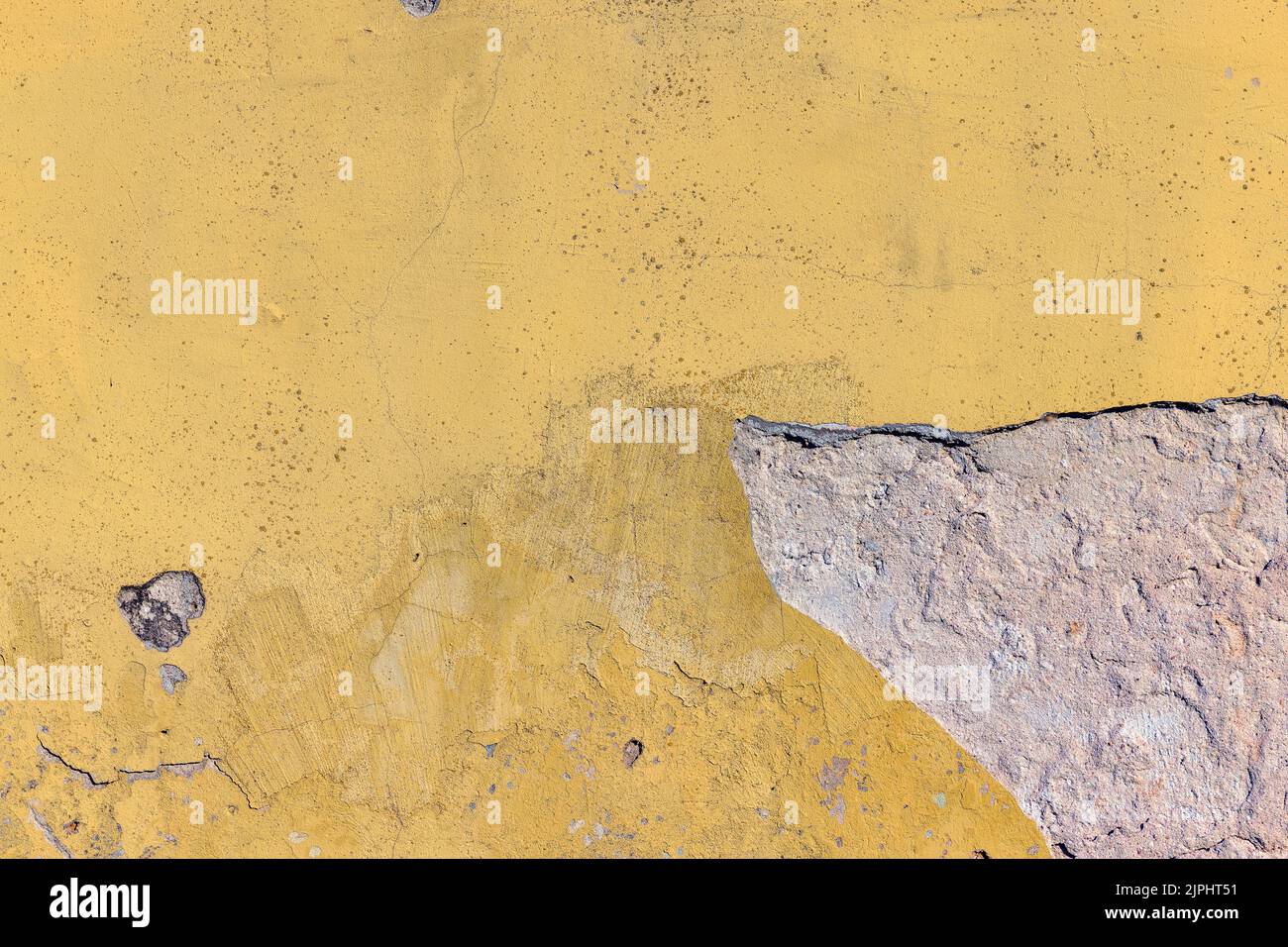 Damaged yellow plaster of a concrete wall, part of a damaged building ...