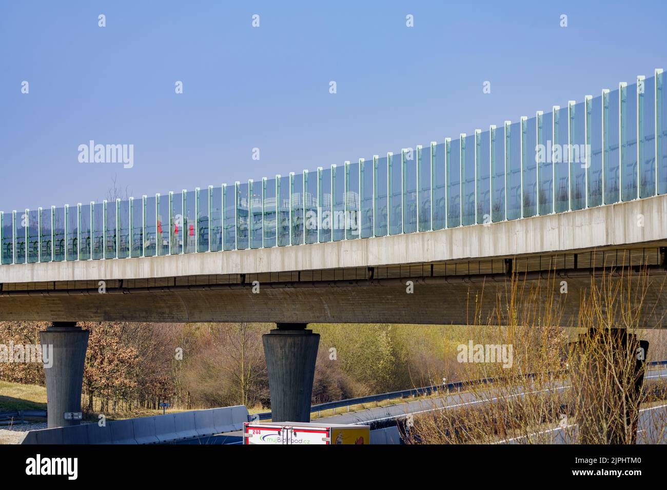 A glass bridge and trucks in the road under the bridge Stock Photo - Alamy