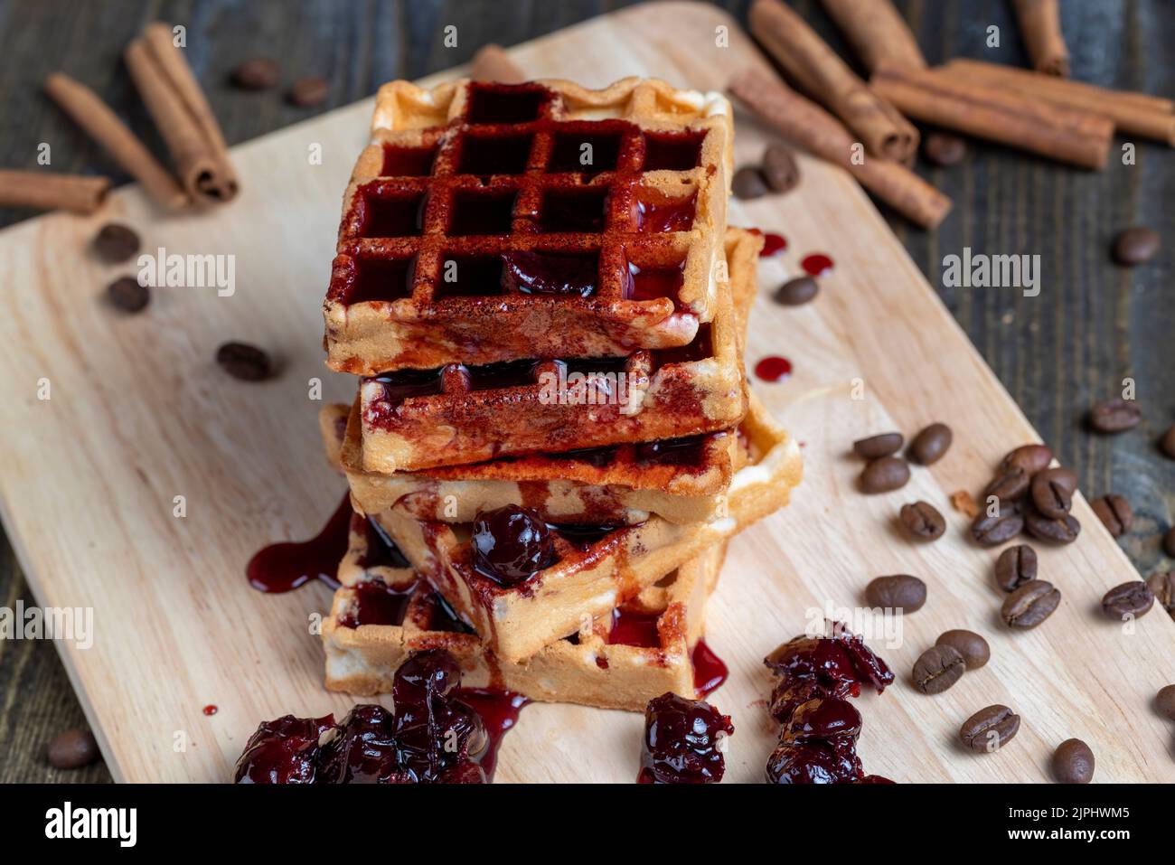 soft waffles with red cherry jam on a serving board, cooking with soft ...