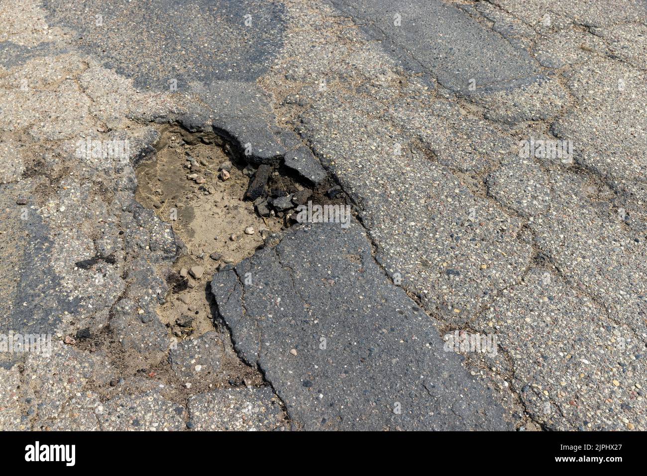An old paved road with a lot of holes and damage, very poor quality of ...