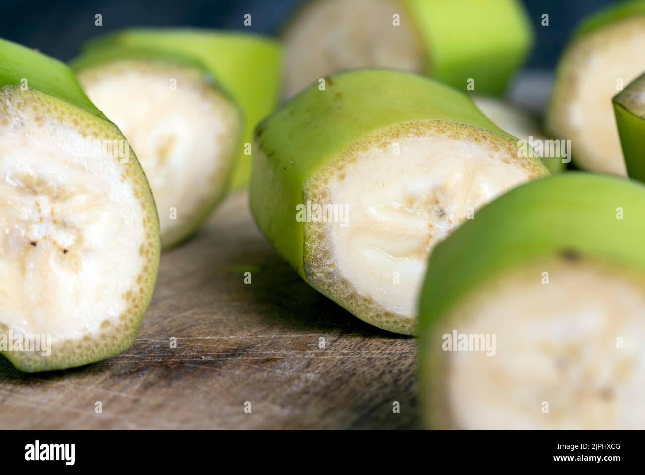 unripe green banana cut into pieces, banana with green peel on the ...