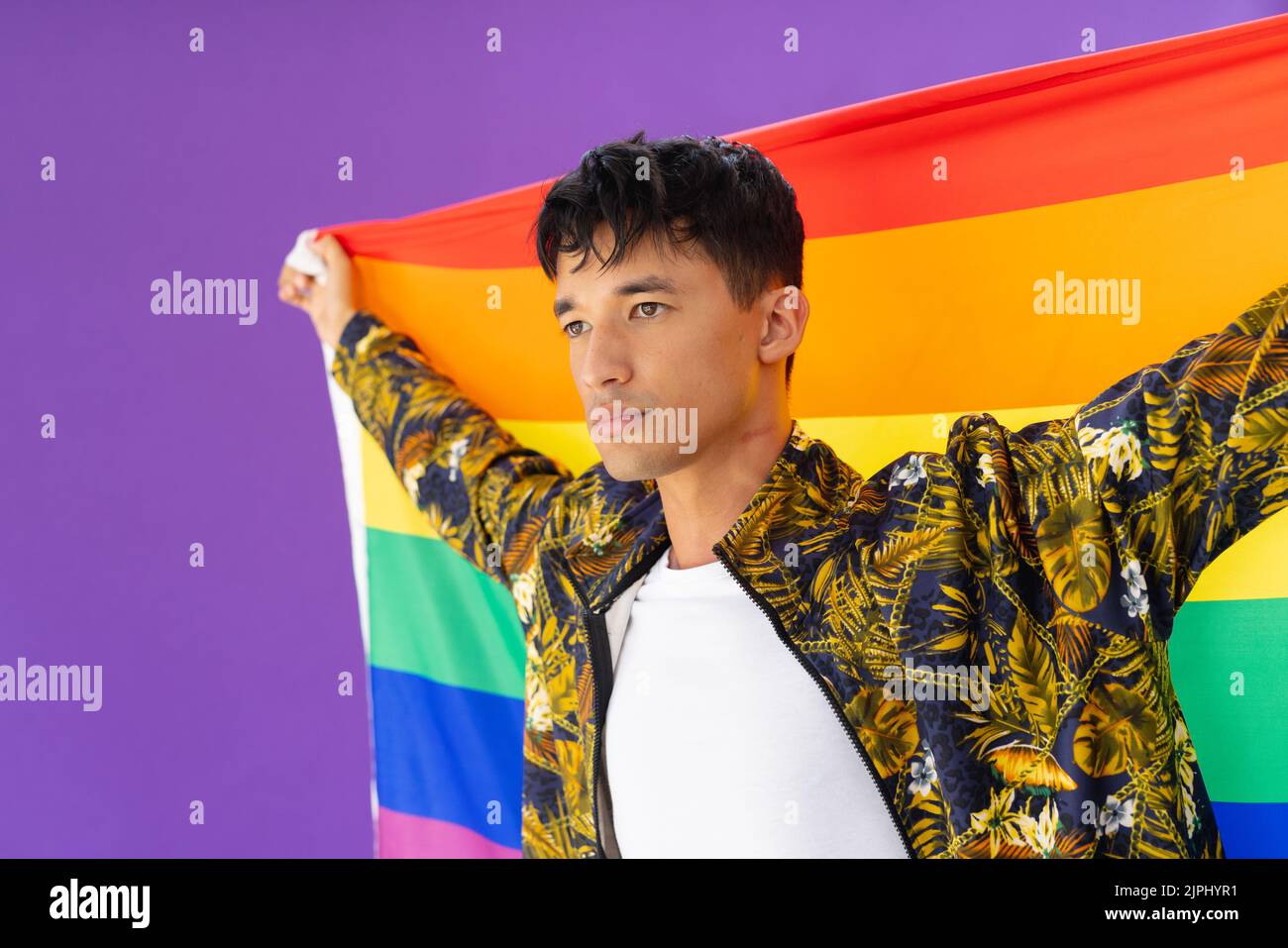 Happy biracial man holding lgbt rainbow flag and smiling on purple ...