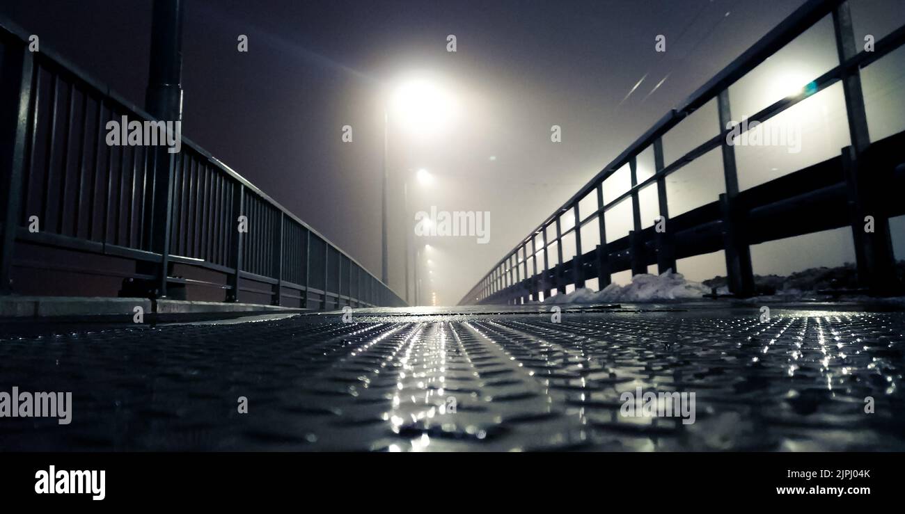 A wet bridge after the rain with a street light illuminating at night ...