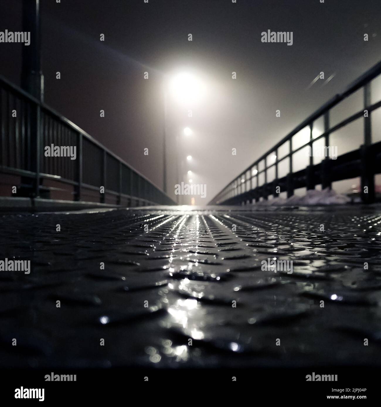 A wet bridge after the rain with a street light illuminating at night ...