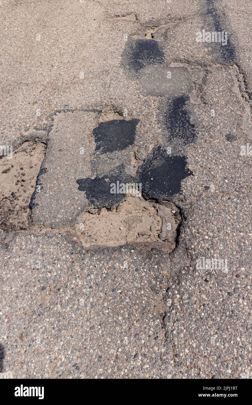 An old paved road with a lot of holes and damage, very poor quality of ...