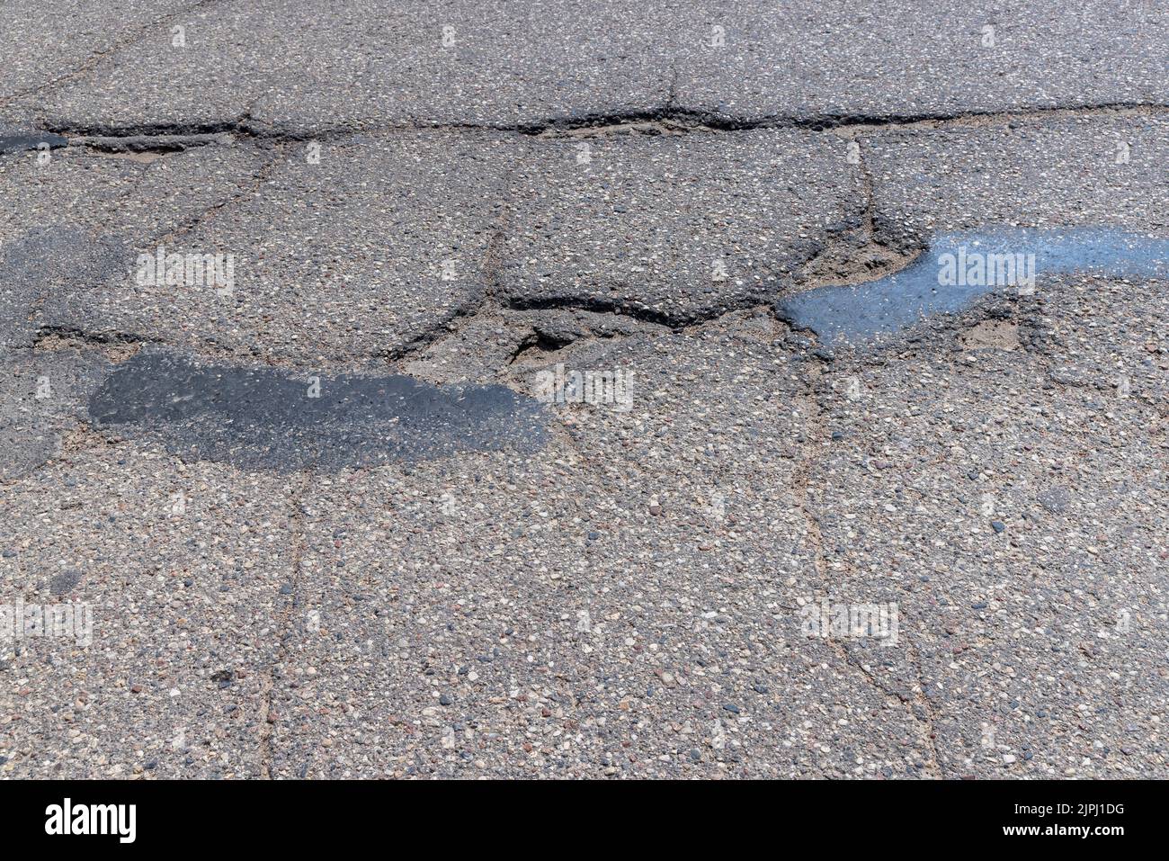 An old paved road with a lot of holes and damage, very poor quality of ...