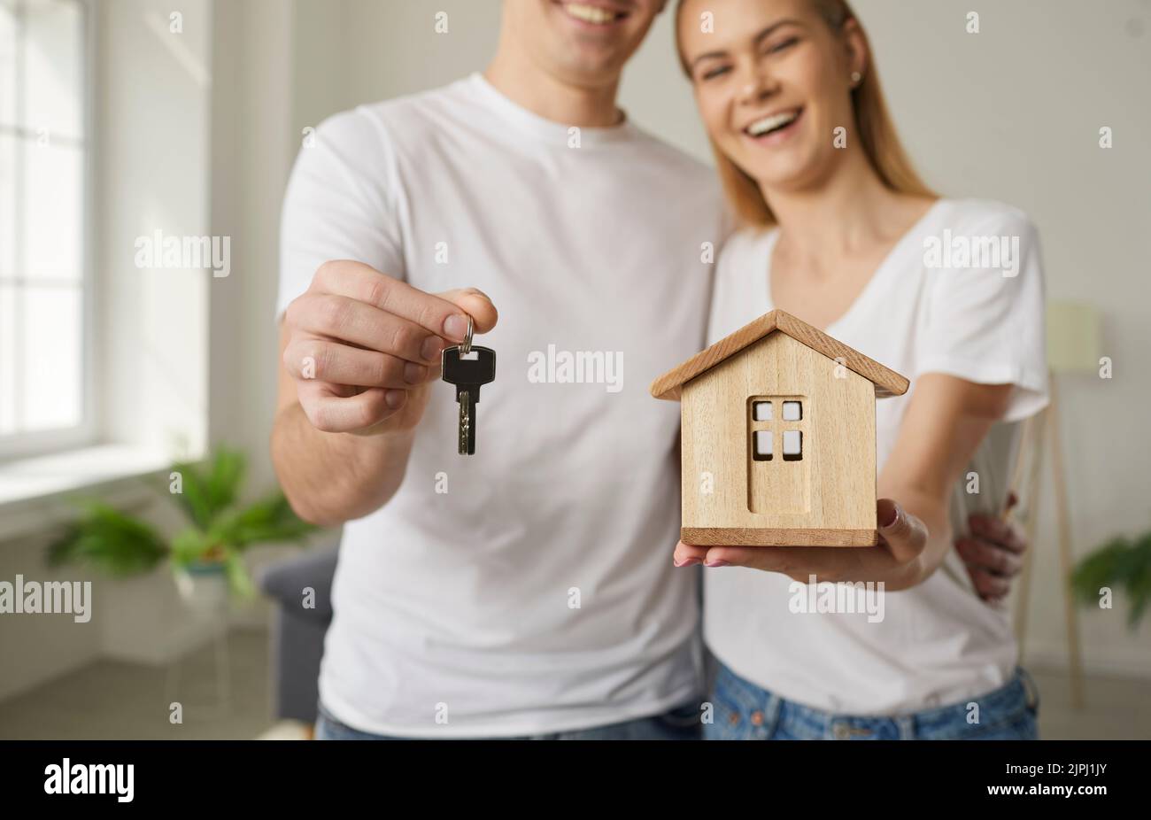 Happy young couple who have bought new house holding toy and keys to ...