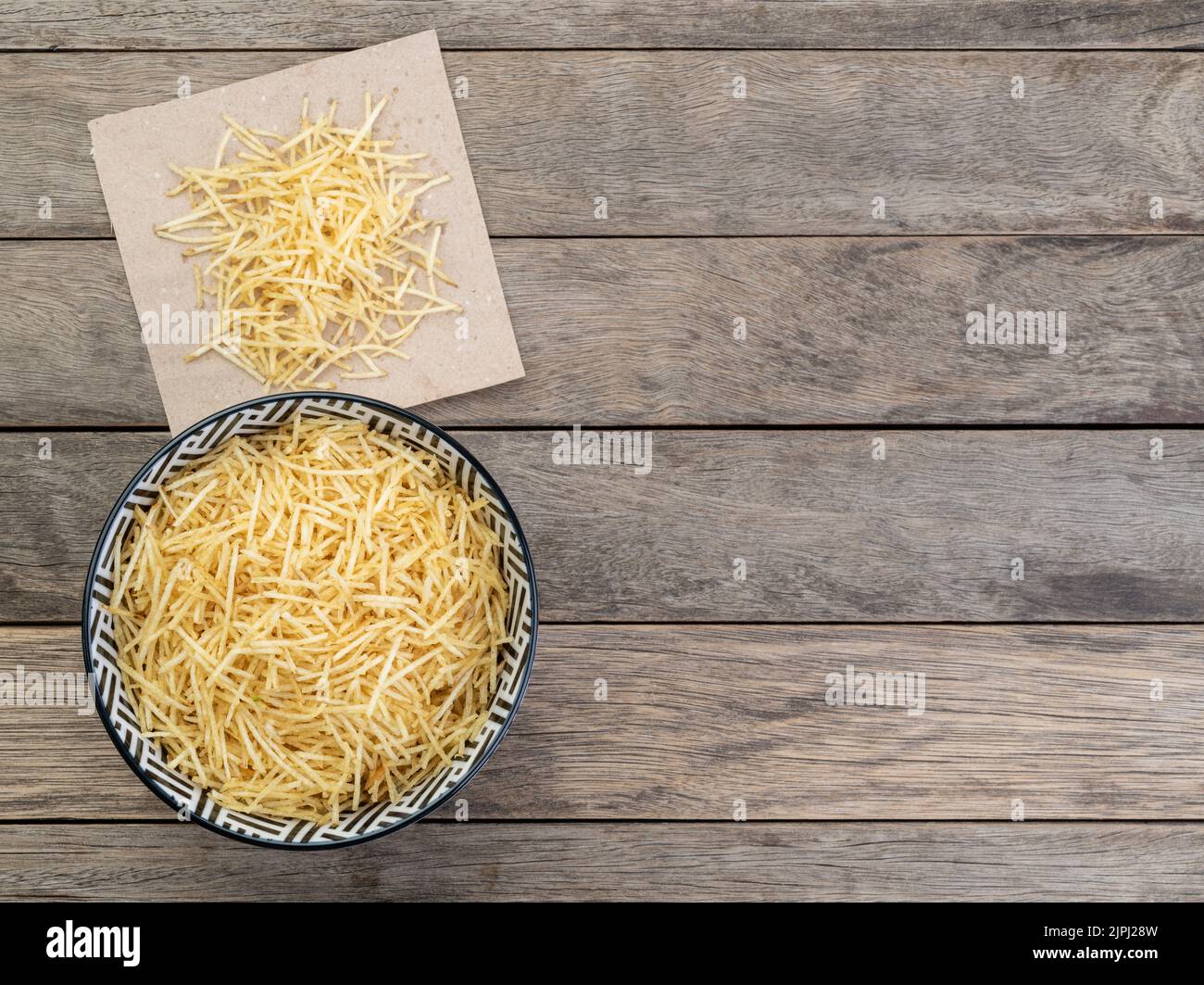 Potato straw or shoestring potato in a bowl over wooden table with copy ...