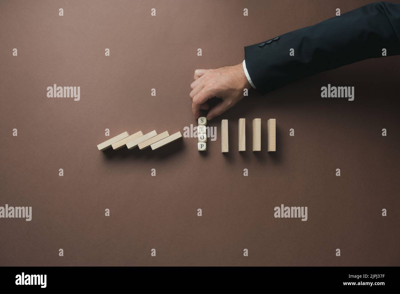 Hand of a businessman stacking wooden cubes with a Stop sign on them in ...