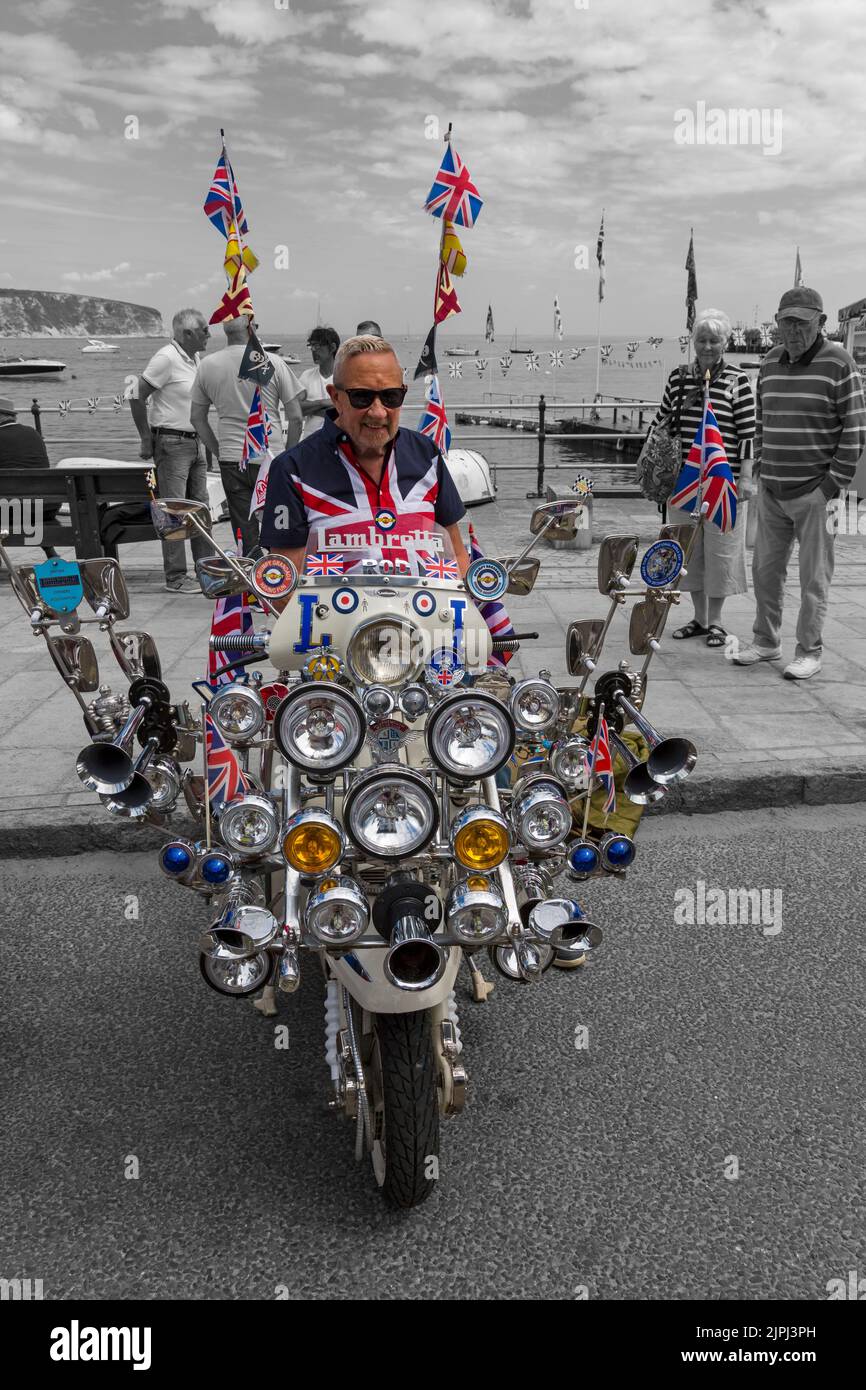 Man sitting on Lambretta on seafront at Swanage, Dorset UK on a hot ...