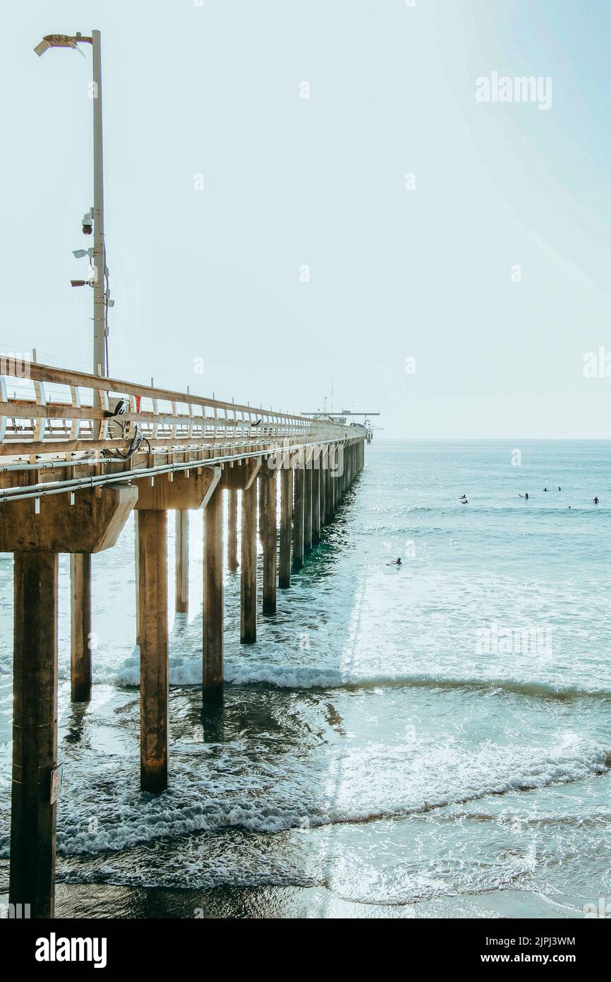 A vertical shot of the La Jolla pier on the ocean with a cloudless sky ...