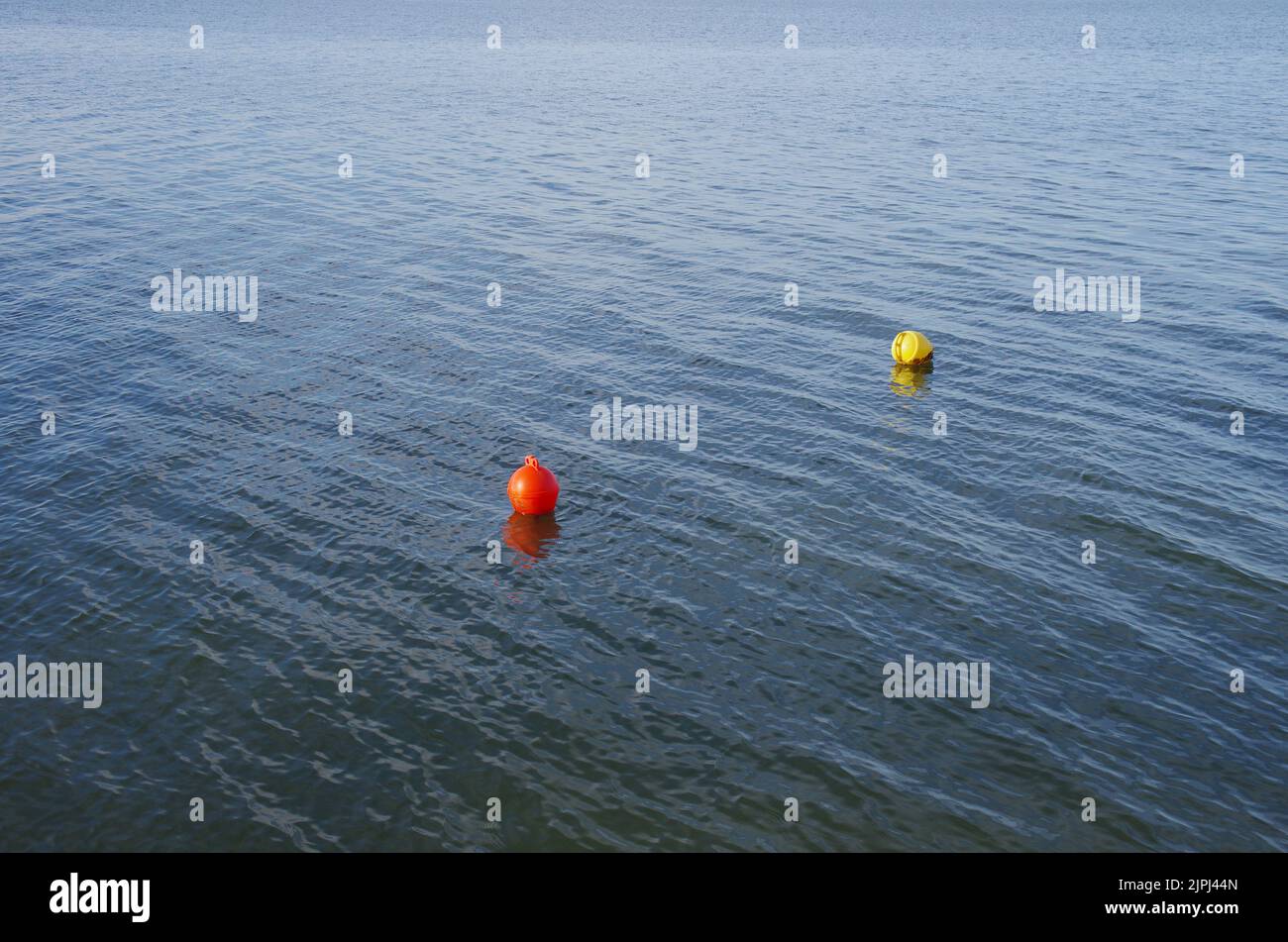 A red and a yellow buoy float on the water Stock Photo - Alamy