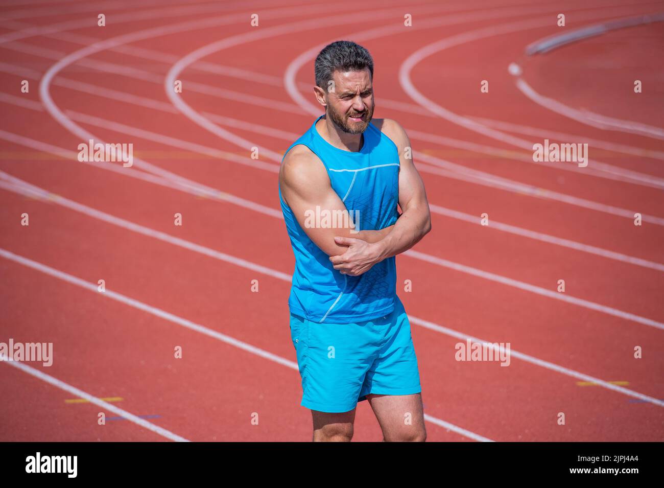 man has injury after exercise on stadium. fitness gym outdoor. muscular ...