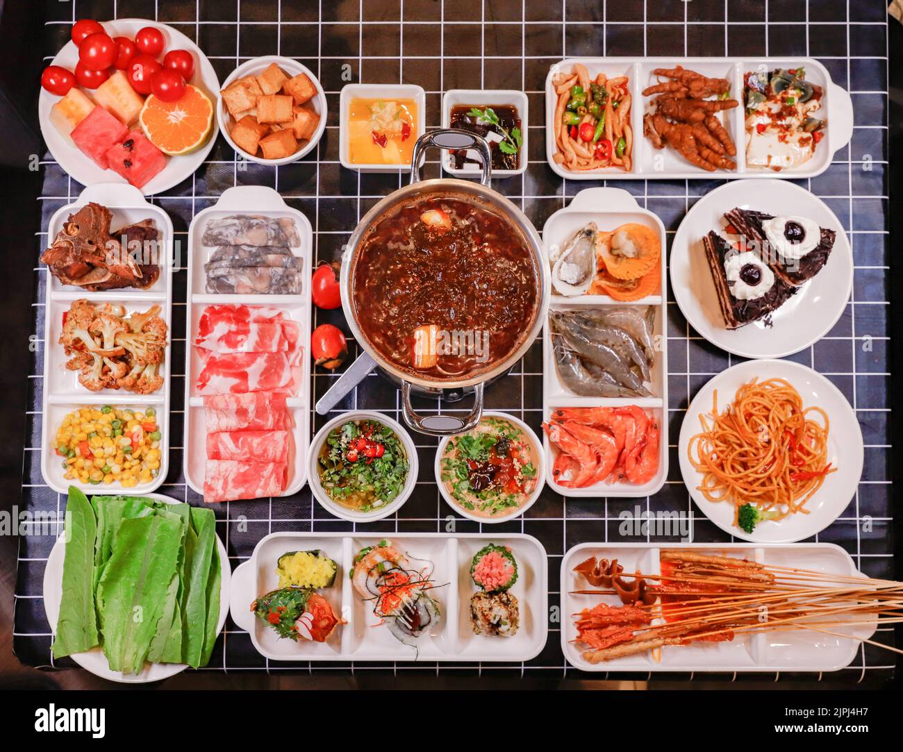 A top view of a restaurant table with hot pot and different appetizers ...